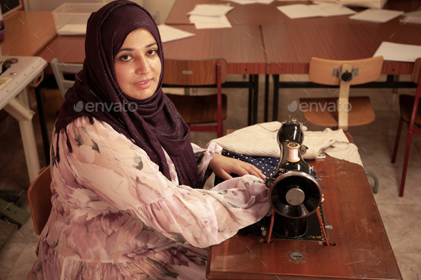 A seamstress of Arab origin sews a garment on her sewing machine. Stock ...