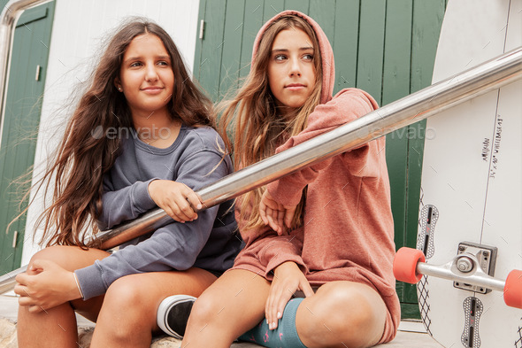 Two teenage girls rest leaning on a metal railing next to their ...