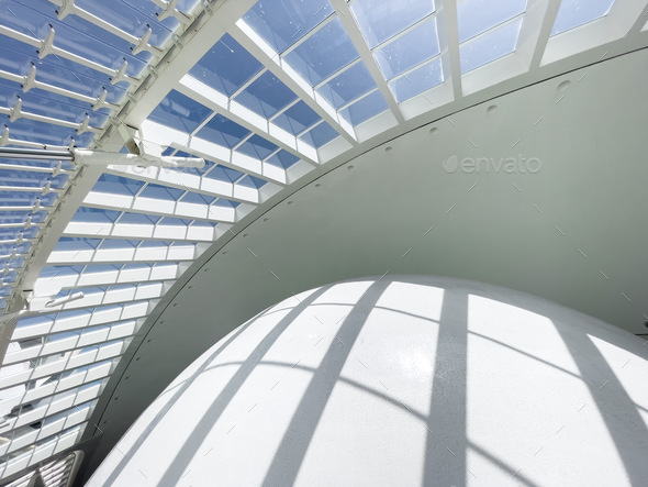 Photograph of a modern architectural building. Sunlight shines through ...