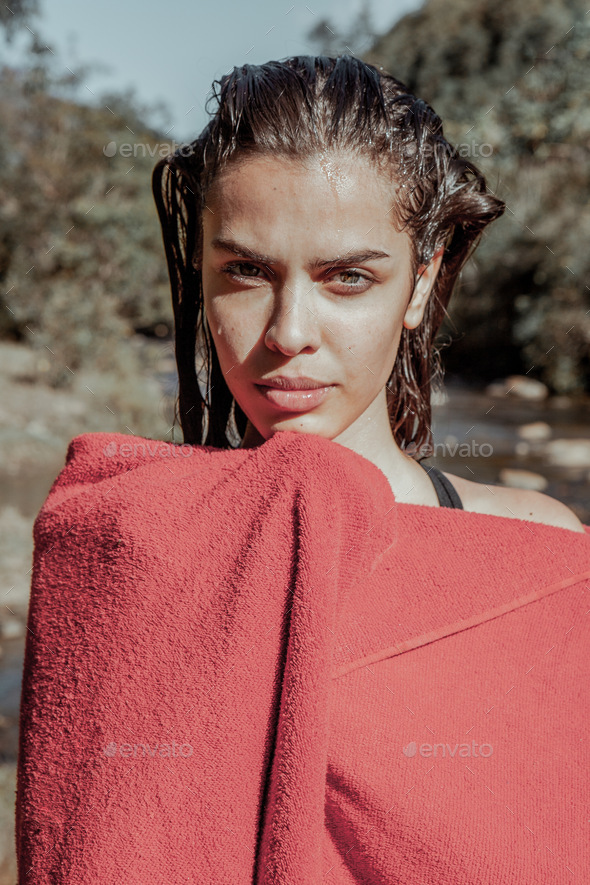 Portrait of a millennial girl drying herself with a red towel after ...