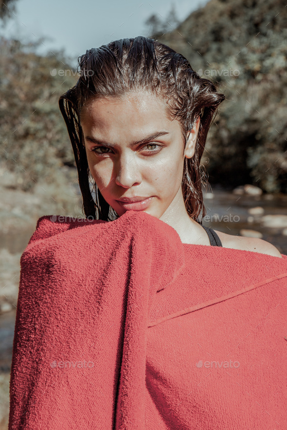Portrait of a millennial girl drying herself with a red towel after ...