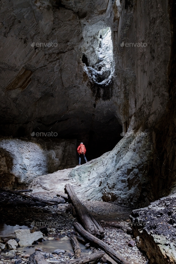 Man inside a cave, admiring the imposing walls and carstic formations ...