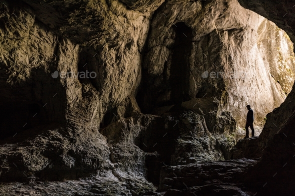 Man inside a cave, admiring the imposing entrance , while being on a ...