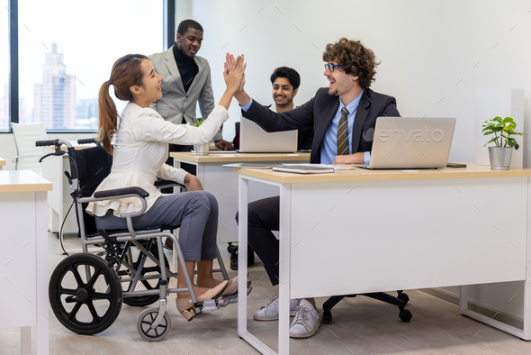 Office workers and woman on a wheelchair in bright office. They are ...