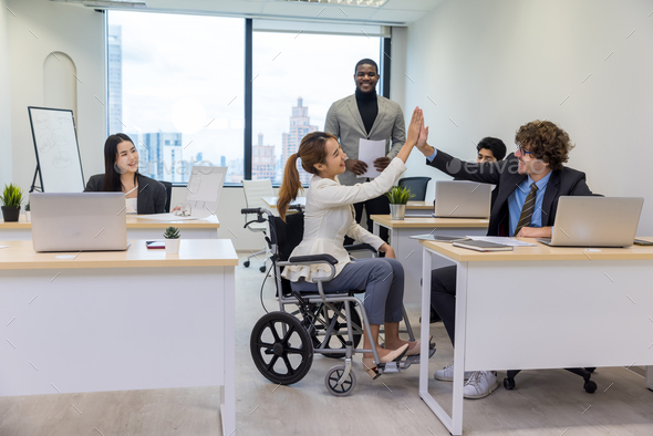 Office workers and woman on a wheelchair in bright office. They are ...