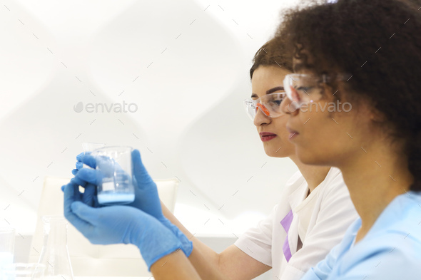 Two medical laboratory scientists wearing glasses working with test ...