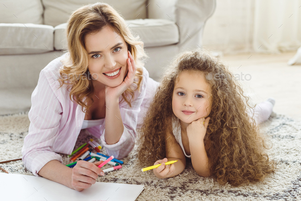 curly daughter and beautiful mother with markers and drawing album looking at camera Stock Photo ...