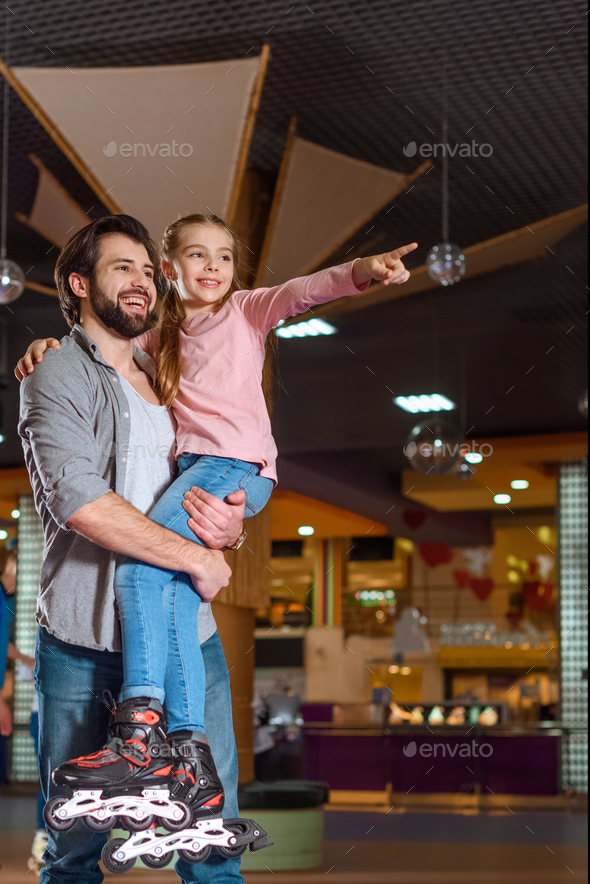 smiling father holding daughter in roller skates on roller rink Stock ...