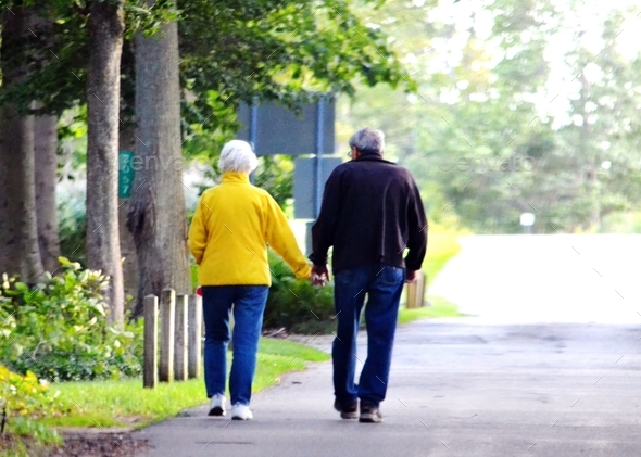 Active baby boomers walking holding hands Stock Photo by maginnislaura