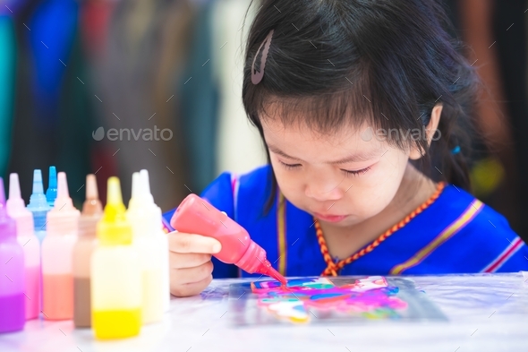 Child cries while working on the art of colored paint from the bottle ...
