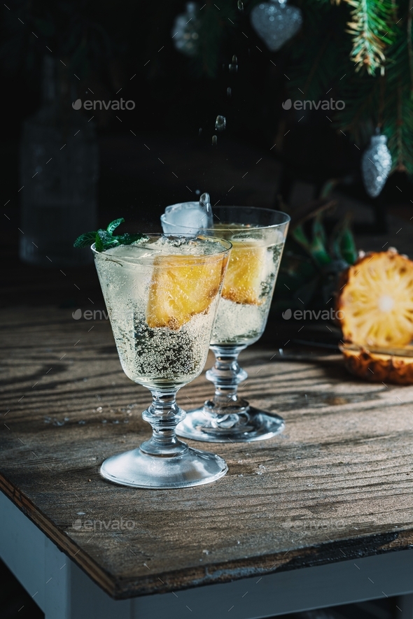 champagne in glass glasses with pineapple in low key on a gold ...
