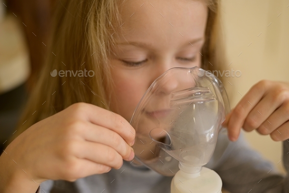 close-up of a sick portrait of a child inhaling with a nebulizer at ...