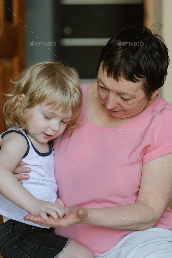 portrait of grandmother and curly grandson holding hands, indoors at ...