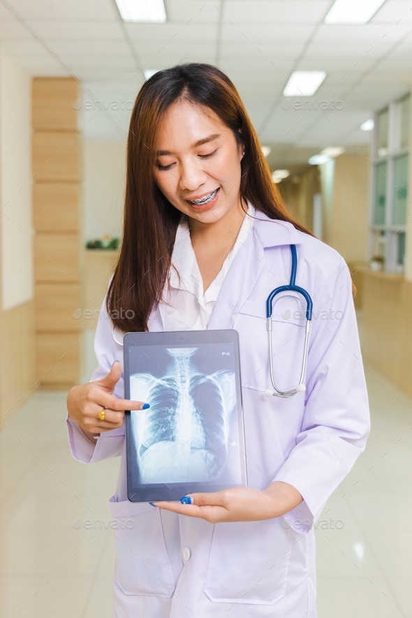 portrait of smart female doctor holding tablet to show X-Ray picture ...