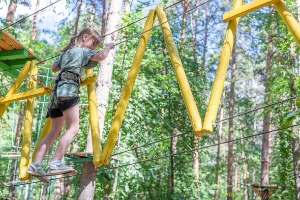 cute girl in forest adventure park, climb on high rope trail. Stock ...