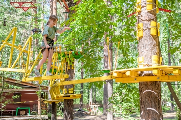cute girl in forest adventure park, climb on high rope trail. Stock ...