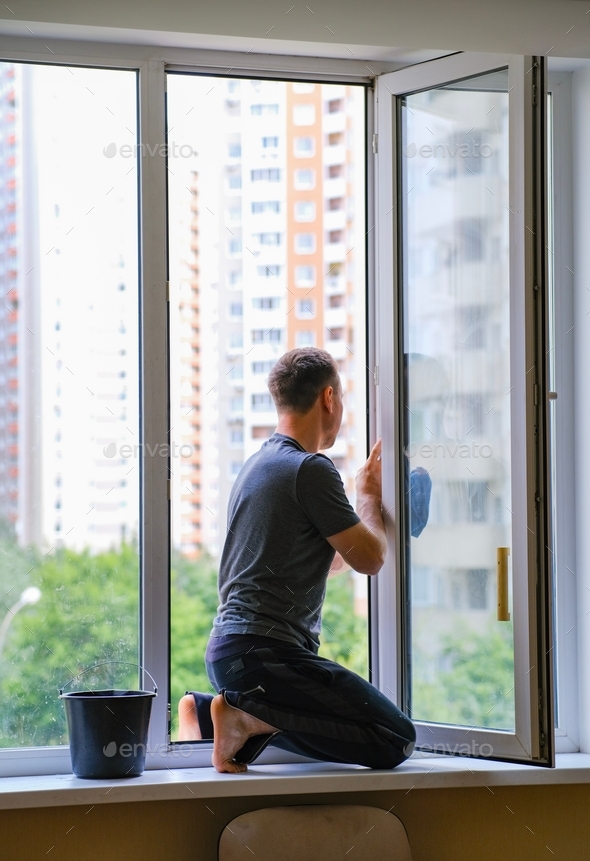 A young slender man washes a window. Household chores. Cleaning and ...