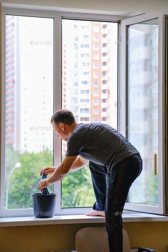 A young slender man washes a window. Household chores. Cleaning and ...