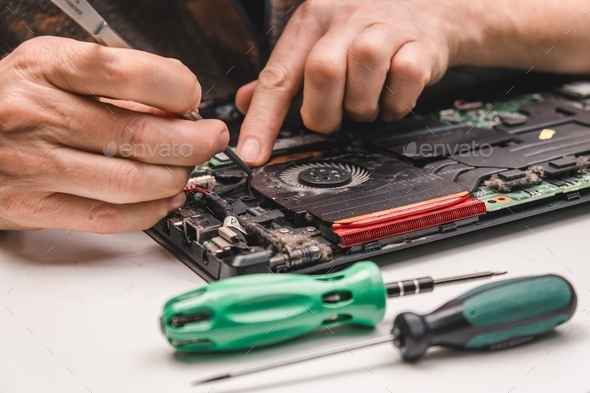 A computer repair specialist disassembles and cleans the laptop cooling ...
