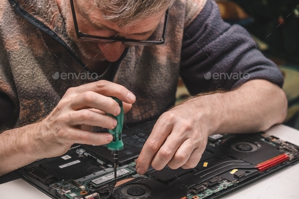 Computer repair specialist installs cleaned laptop cooling system into ...