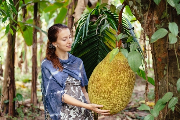 Young female tourist in Asia holding jackfruit in hands on fruit ...