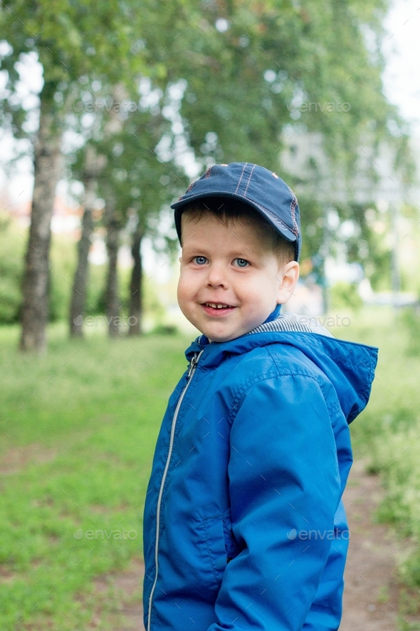 Blue-eyed boy in a cap. Boy in a blue windbreaker for a walk. Handsome ...