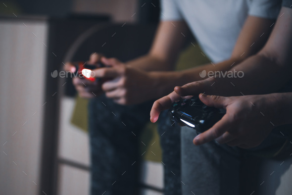 The hands of two men playing with joysticks from a game console in the ...