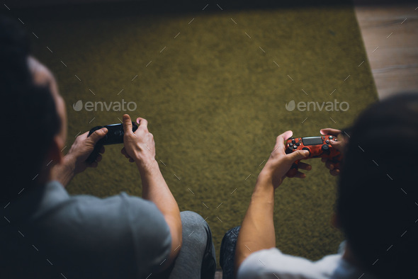 The hands of two people with joysticks who play the console at home in ...