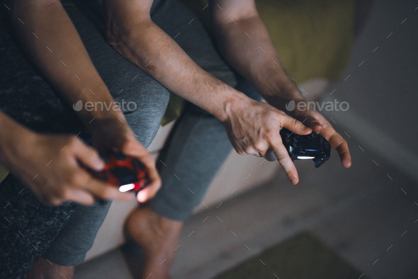 The hands of men with joysticks who play the console at home in the ...