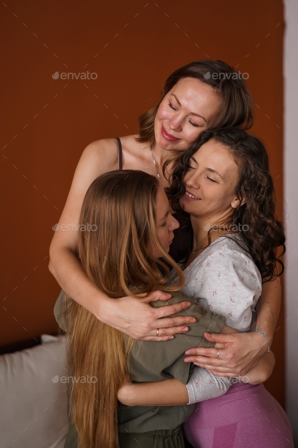three girlfriends hugging when they meet Stock Photo by elmizaismagilova