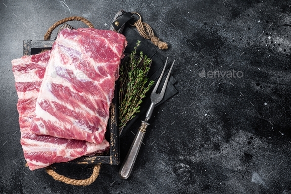 Fresh rack of raw pork spare ribs with herbs. Black background. Top ...