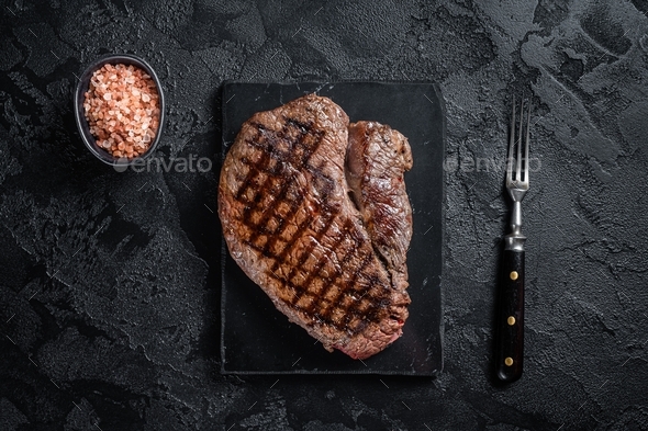 Grilled top sirloin or rump steak on a marble board. Black background ...