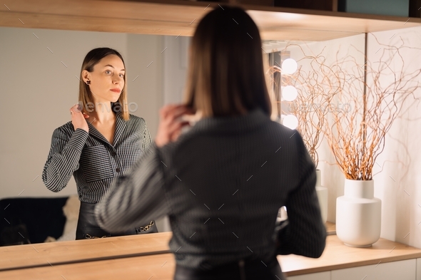 Confident woman looking to her reflection into the mirror Stock Photo ...