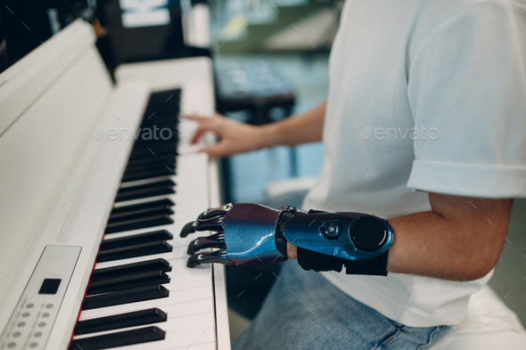 Young disabled man play on piano electronic synthesizer with artificial ...