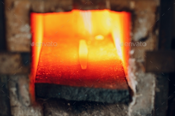 Blacksmith forge oven with hot flame. Smith heating iron piece of steel ...