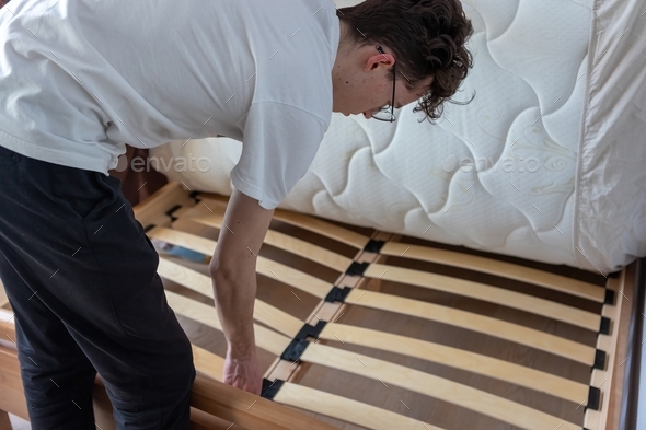 A man checks the base of the bed under the mattress in the bedroom. How ...