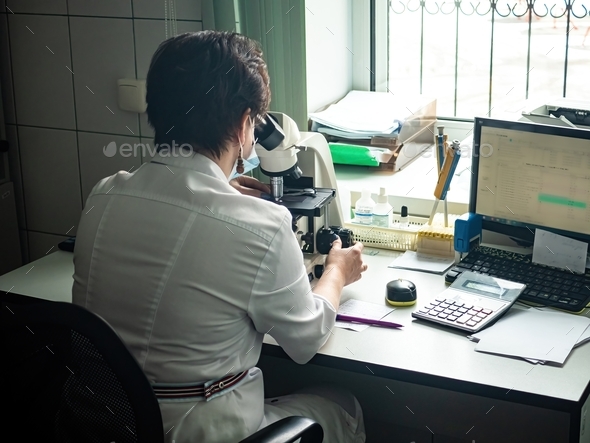 Laboratory technician, laboratory assistant, looks into a microscope ...
