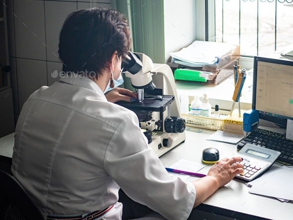 Laboratory technician, laboratory assistant, looks into a microscope ...