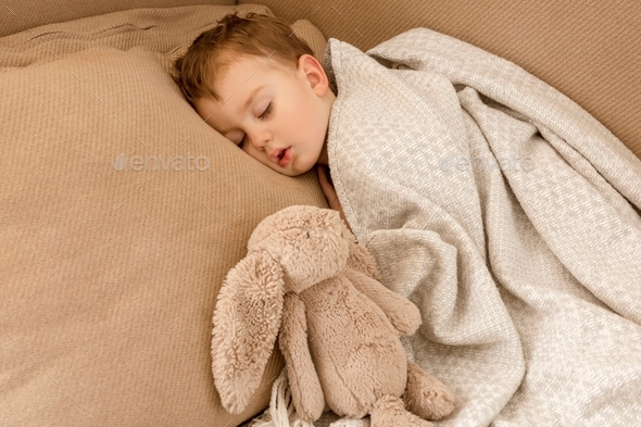 Little, cute caucasian boy sleeping on couch at home. Child taking day ...