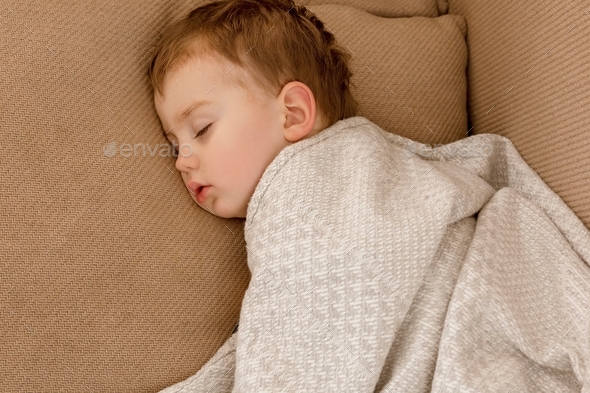 Little, cute caucasian boy sleeping on couch at home. Child taking day ...