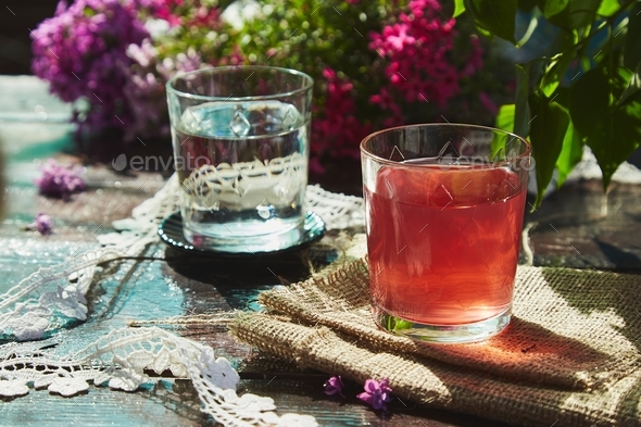 Rustic Summer Cocktail And Glass Of Water Among Spring Flowers In The