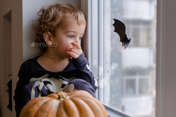 A brooding little boy in a skeleton costume for Halloween is sitting at ...