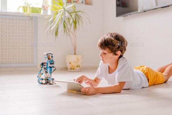 Kid programming robot from plastics details and programmed on tablet ...