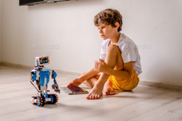 Kid programming robot from plastics details and programmed on tablet ...