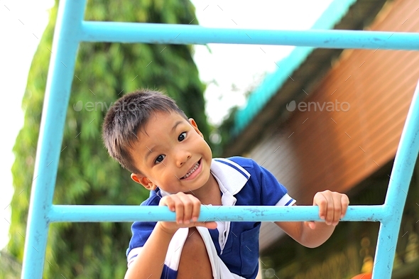 Happy asian child boy playing and climbing a steel bar toy at the ...