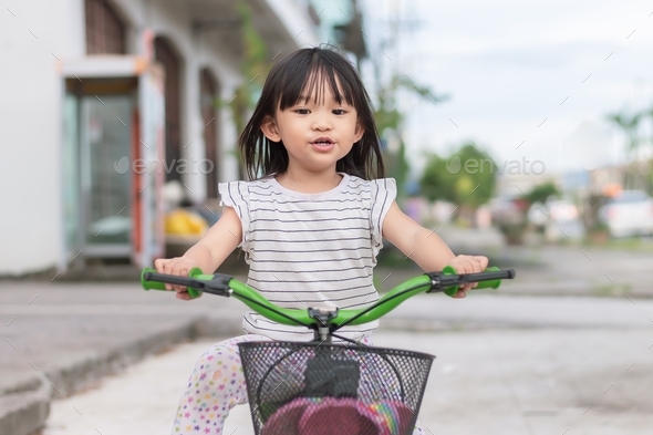 Portrait image of Happy cute Asian child girl ride a bike at the park ...