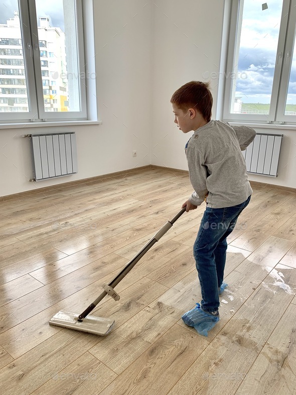 Child wash cleaning with a mop the floor in an empty apartment ...