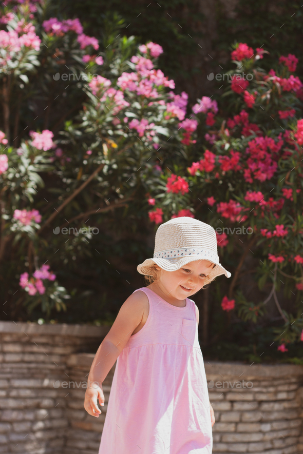 little girl in a pink dress and a straw hat against the background of ...