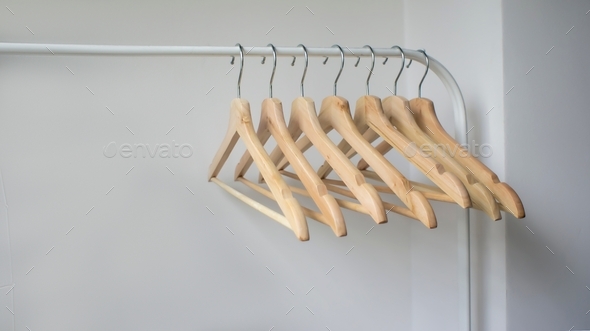 Wooden clothes hangers hanging on a rail on a white wall minimalism ...