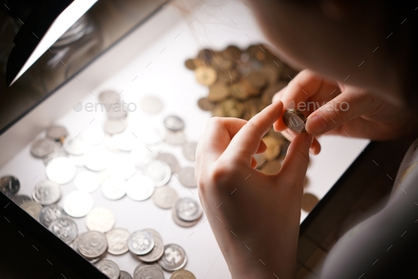 Checking and inspecting different coins, searching for a rare coin ...